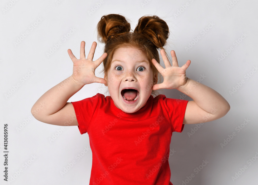 Excited Little girl with freckles and red hair screams loudly with ...