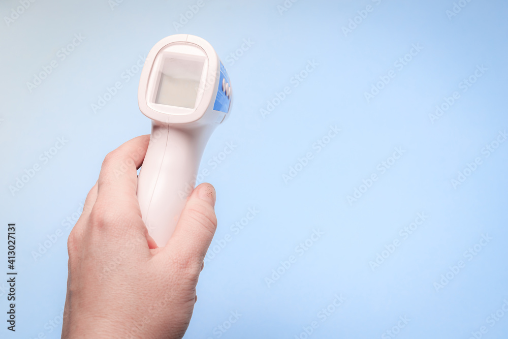 infrared thermometer on a blue background in your hand. the thermometer ...