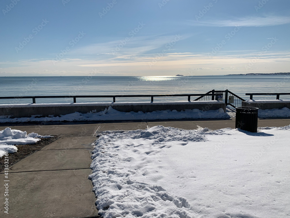 Vistas del camino y la playa nevados al borde del mar en un día soleado ...
