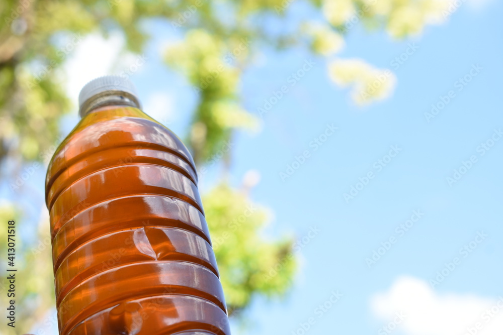Botella de miel de abeja natural con fondo de arboles y cielo azul ...