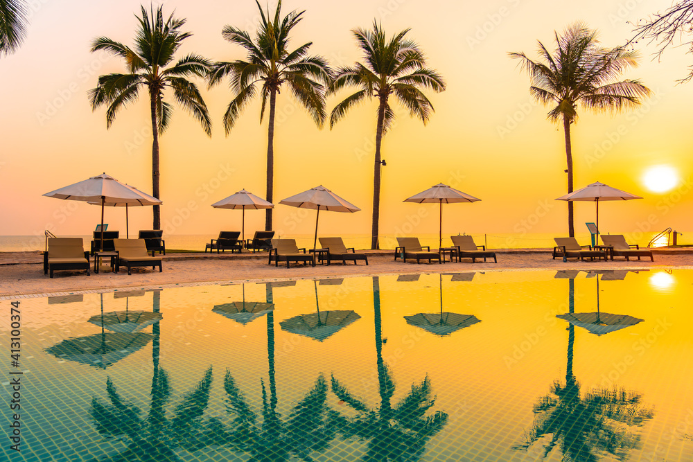 Umbrella and chair around outdoor swimming pool with sea beach ocean at ...