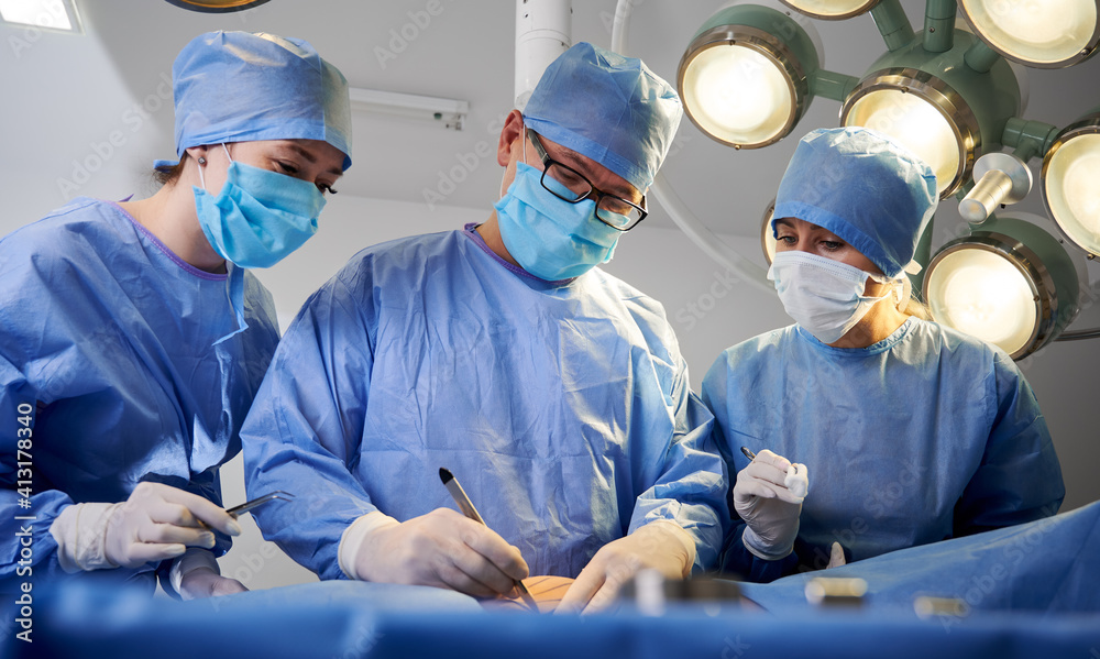 Doctors performing aesthetic surgery while patient lying on operating ...