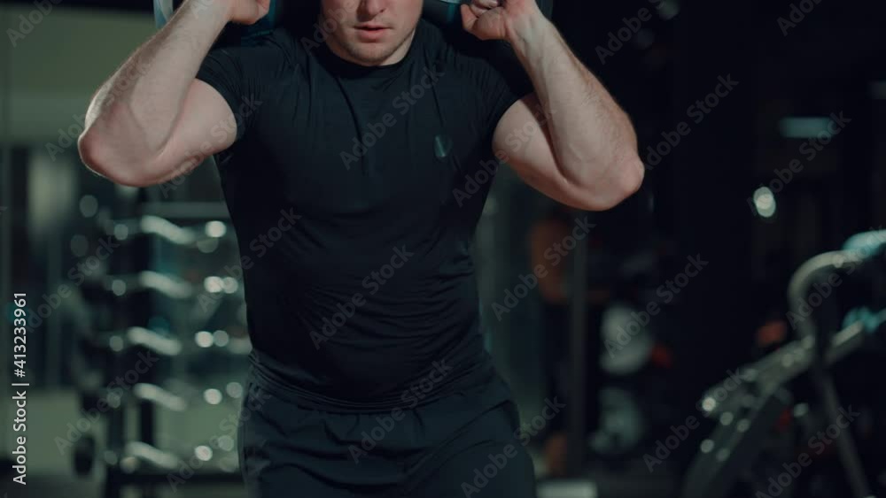 Muscular man in black sportswear carrying sand bag on shoulders and ...