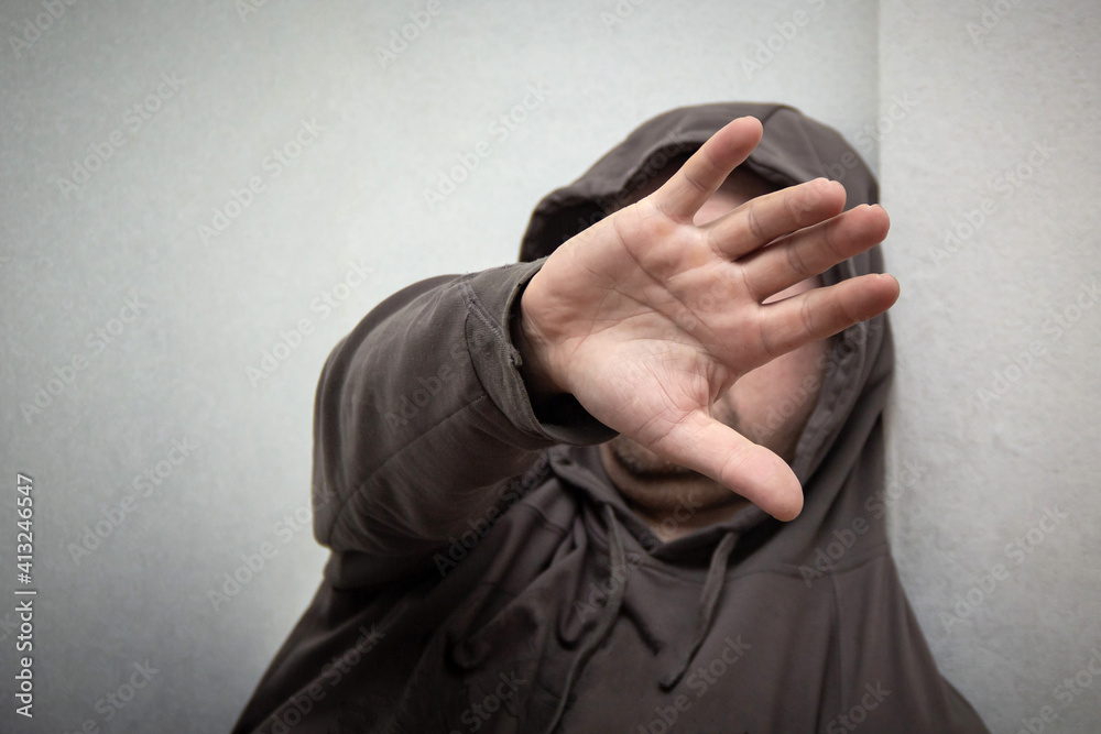 Man in grey hood hiding his face with the hands, show stop sign. Stock ...