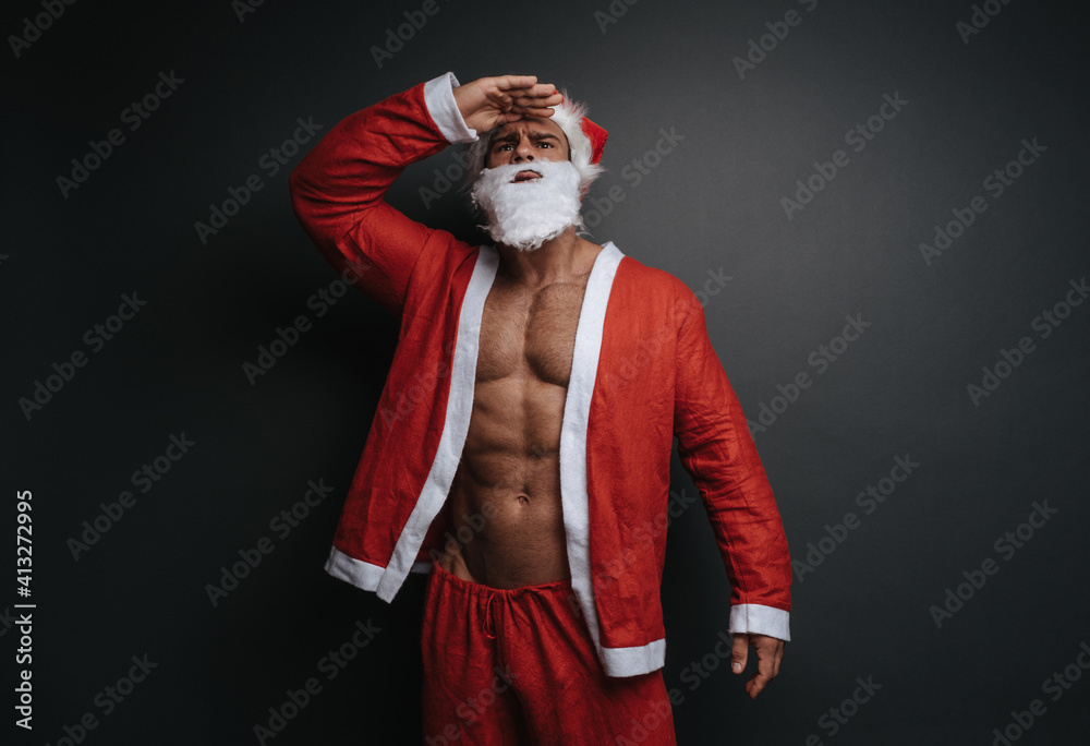 Shirtless muscular man in Santa Claus costume in studio. Emotional ...