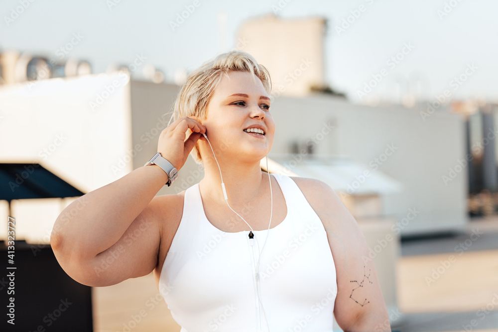 Happy curvy woman standing on a roof. Young oversized female taking a ...