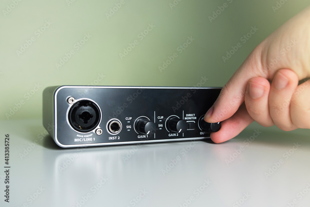 Hand plugin a turning a knob of an external USB Sound card. Home studio ...