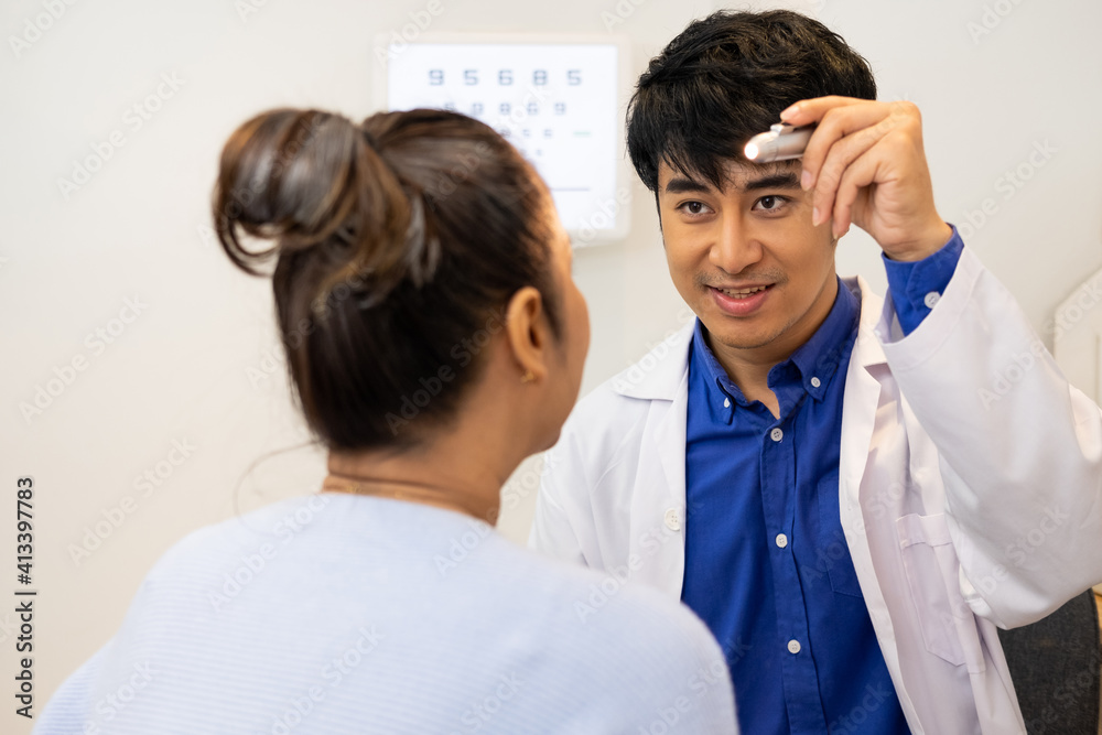 Selective focus at Optometrist face. While doctor using penlight and ...