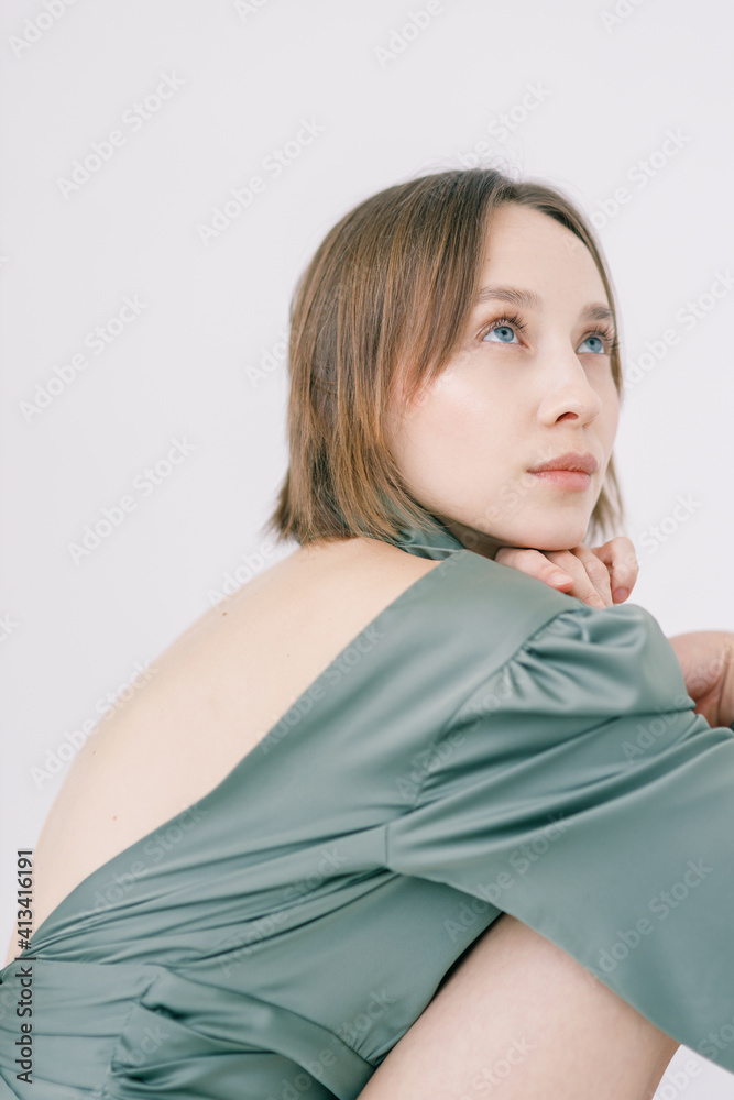 Portrait of a young beautiful girl sitting on a chair in a bright ...
