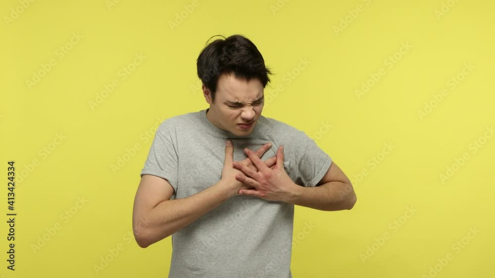 Young guy in gray t-shirt touching his chest and grimacing from sudden ...