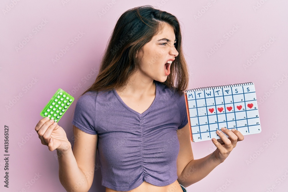 Young caucasian woman holding birth control pills and menstrual ...