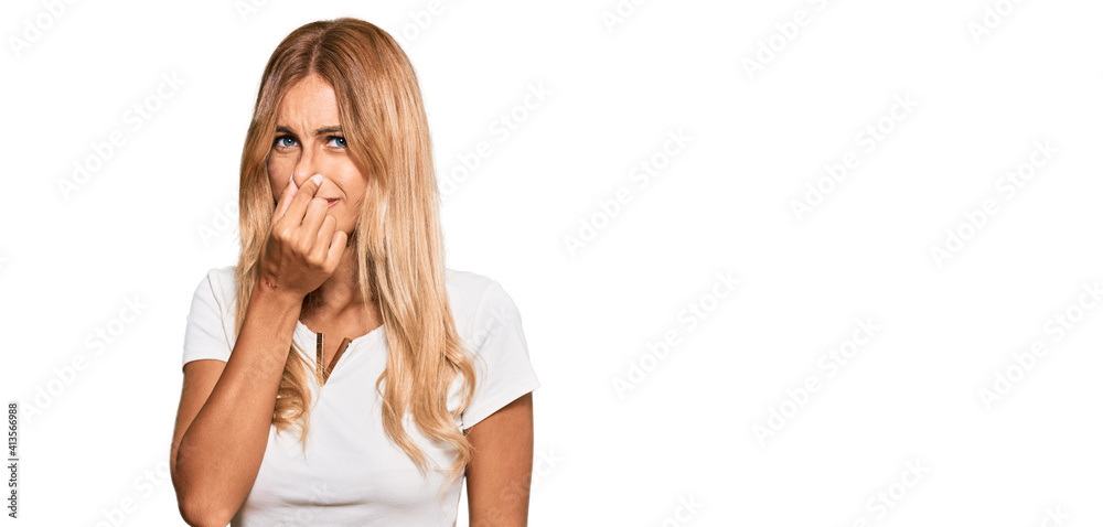 Beautiful blonde young woman wearing casual white tshirt smelling ...