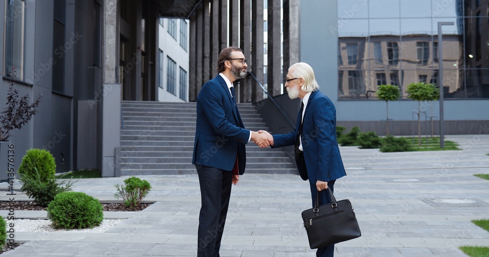 Caucasian senior businessmen in suits and ties meeting outdoor at ...