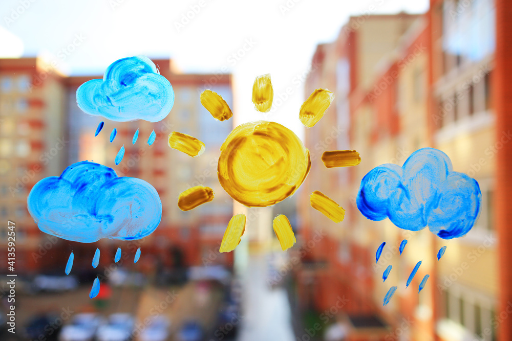 Drawing on the window with paints with a city background. Clouds and ...