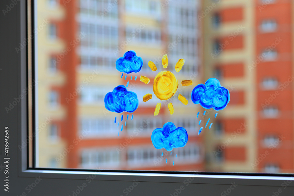 Drawing on a window with a city background. Clouds and the sun are ...