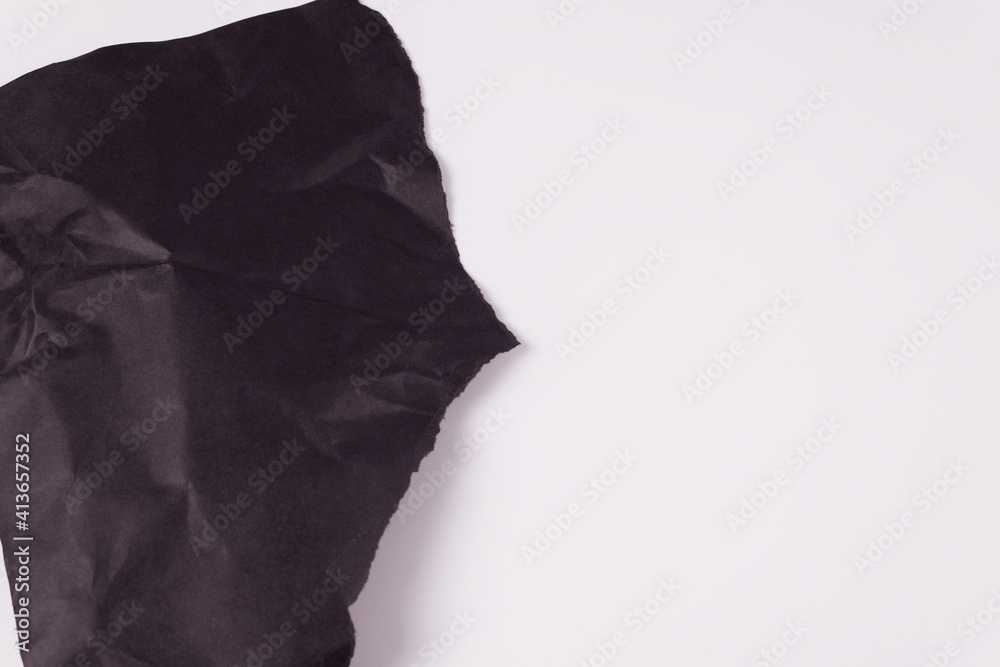 one sheet of black crumpled paper lies on the left side of the frame ...