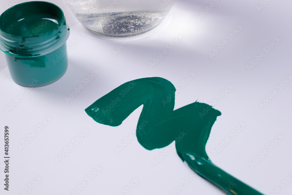 side view of a smear of green color and next to an open jar of green ...