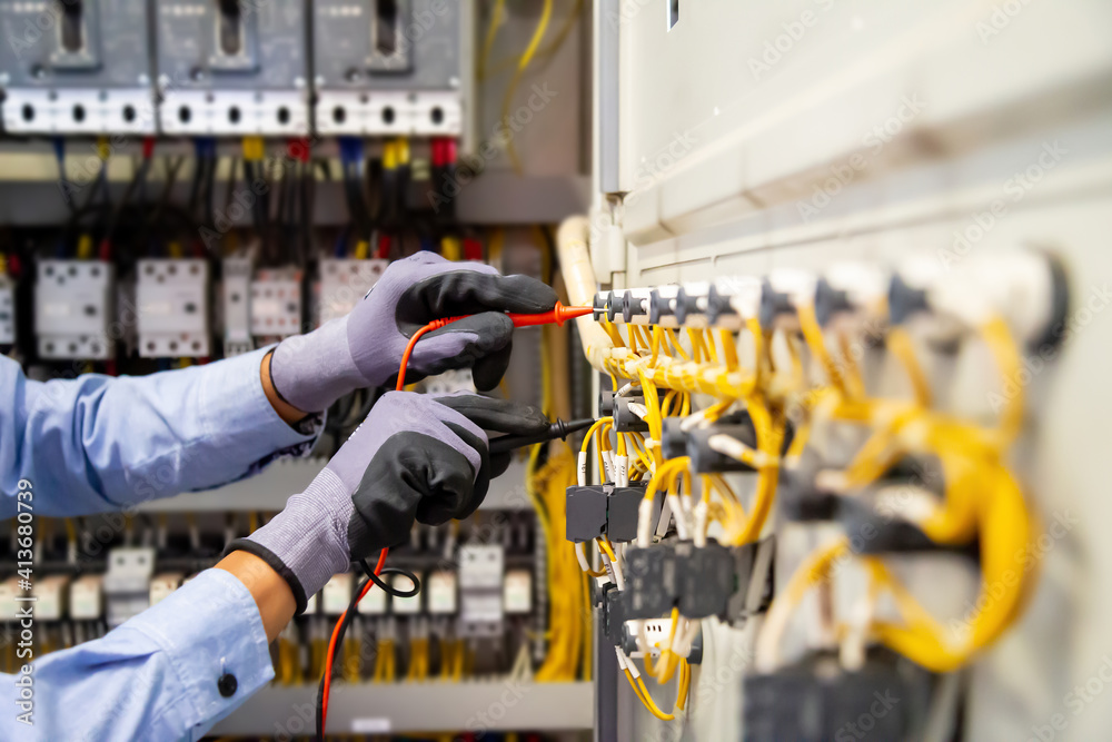 Electrical engineer using digital multi-meter measuring equipment to ...