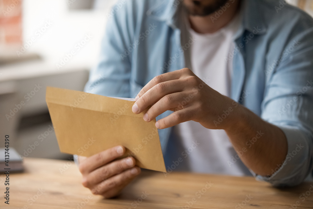 Crop close up of man sit at desk hold open envelope with postal letter ...