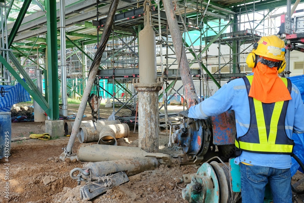 Workers are controlling the tripod rig machine is drilling holes in the ...