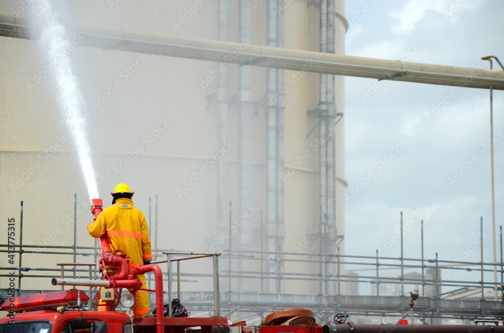 Fireman use fire hose water spray from fire truck to the Large chemical ...