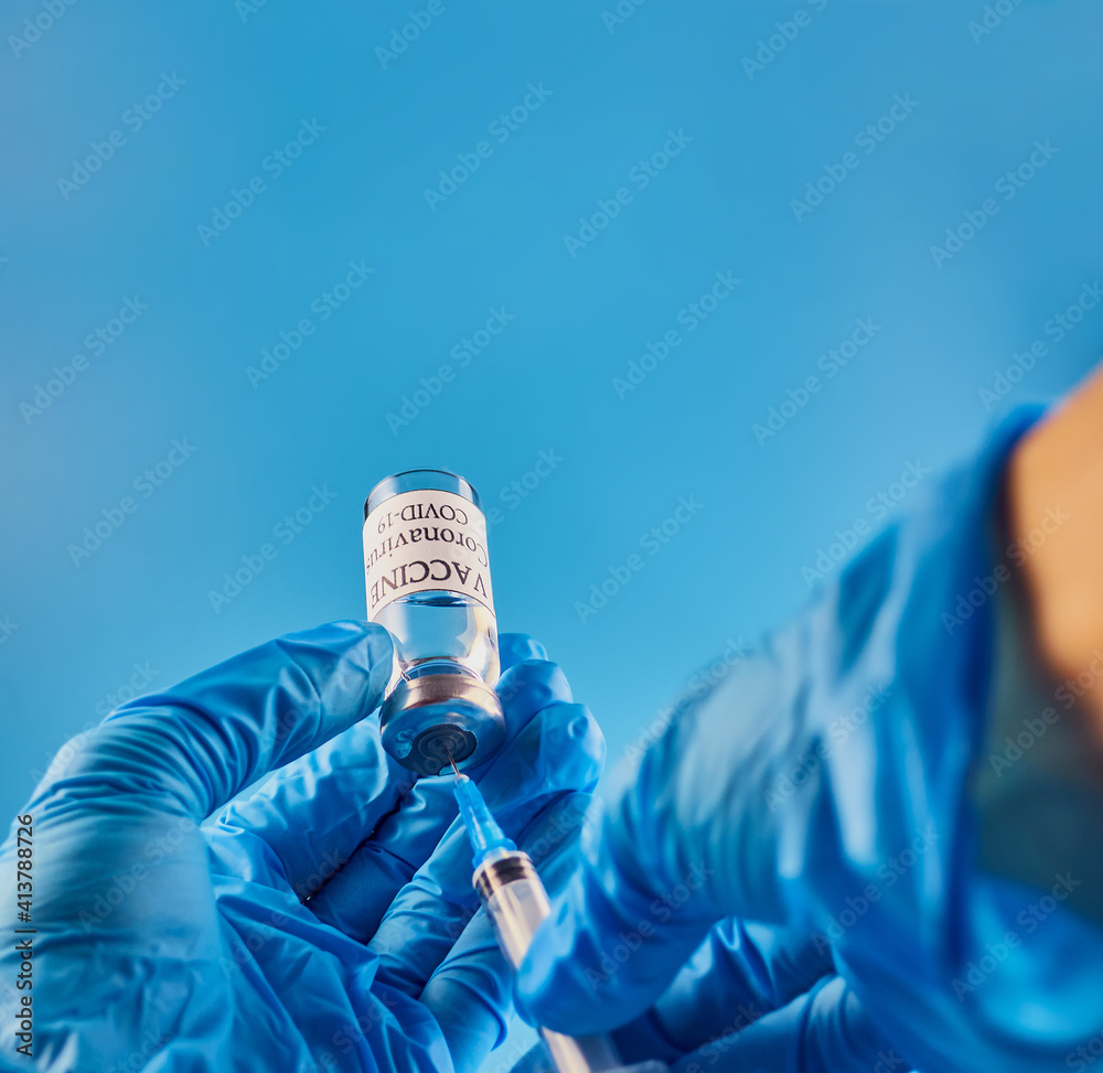 A bottle of COVID-19 vaccine and a syringe with an injection needle ...