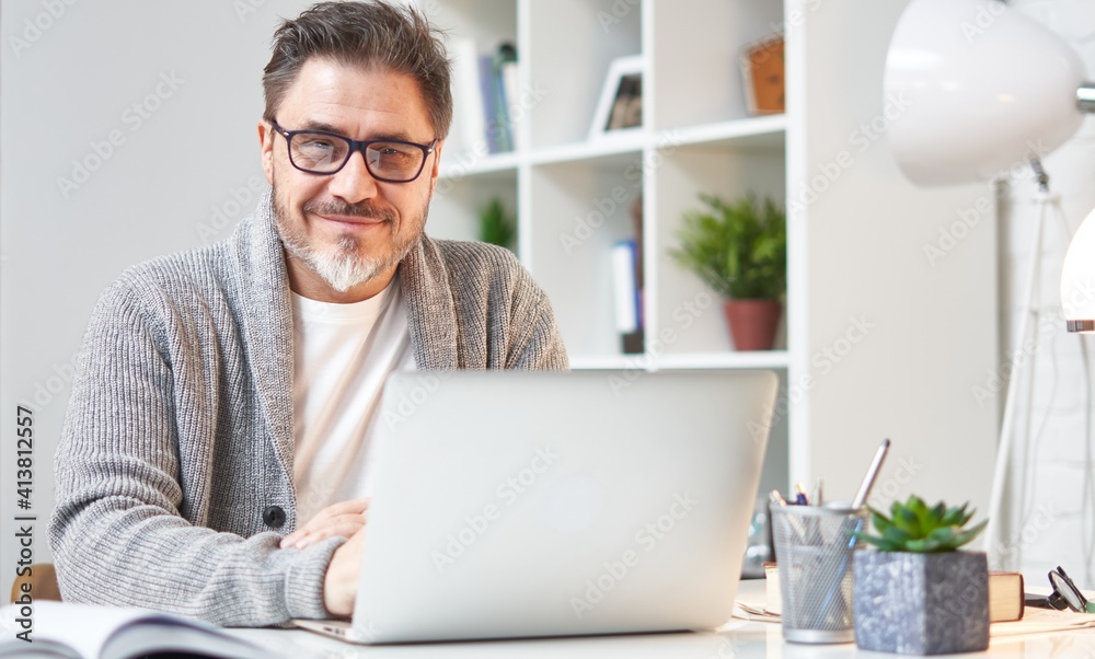 Happy older man working online with laptop computer at home sitting at ...