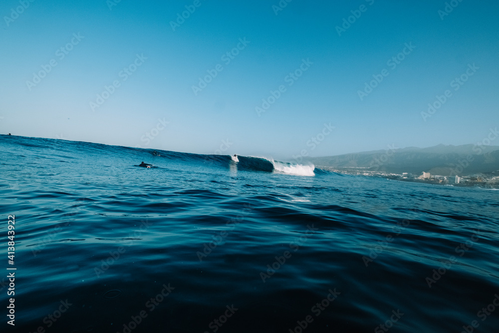Pulled-back view of a perfect wave breaking and a surfer paddling Stock ...