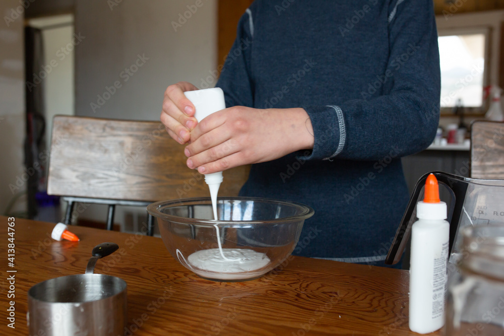 Boy pouring glue into bowl to make slime Stock Photo | Adobe Stock