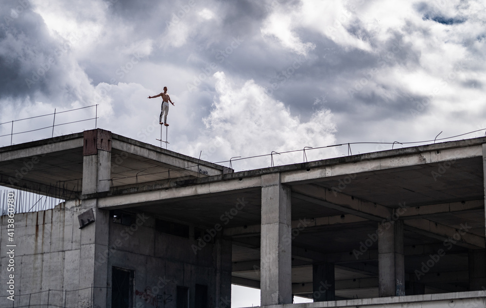 Man standing on the edge of rooftop unfinished building with dramatic ...