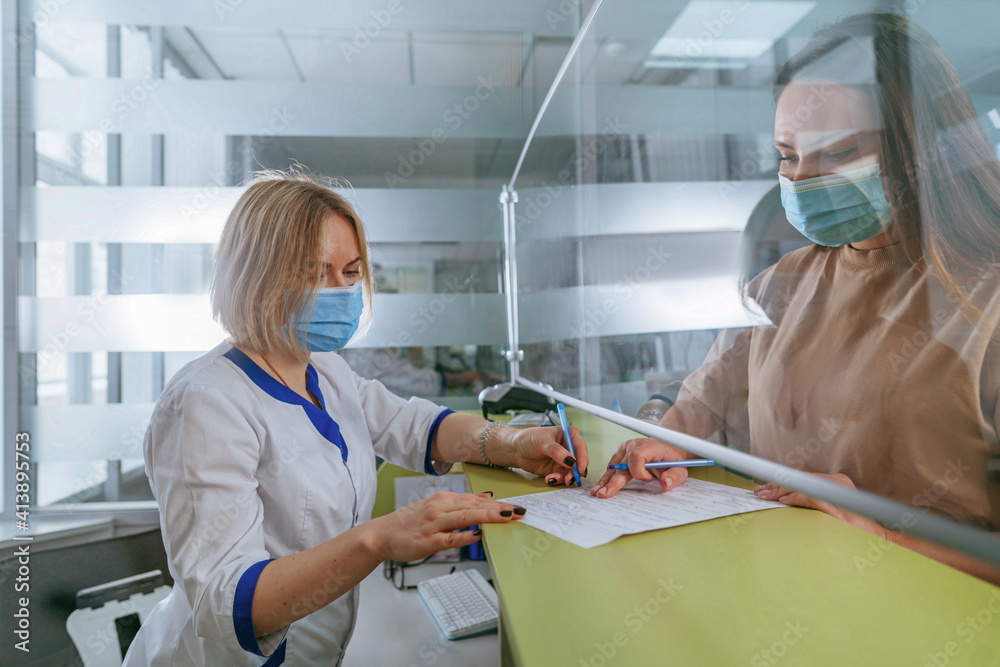 Female doctor or nurse explaining patient how to fill medical form at ...