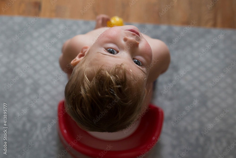 Overhead portrait of cute shirtless baby boy urinating while sitting on ...