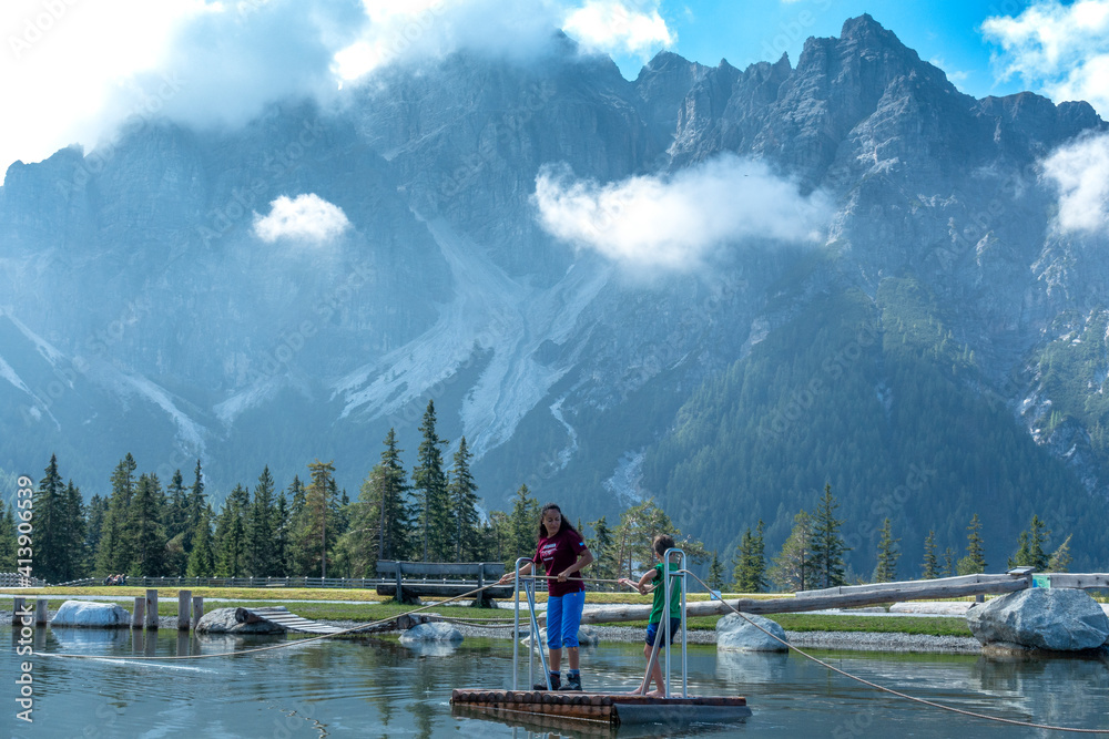 Mother and son pulling a raft to cross the pond of a water playground ...