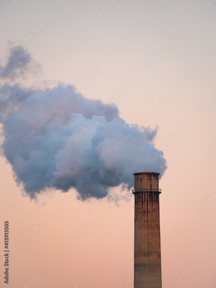 Dense smoke and steam coming out from the industrial chimney ...