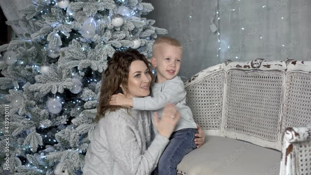 A beautiful little boy and his mother hug and pose for the camera ...