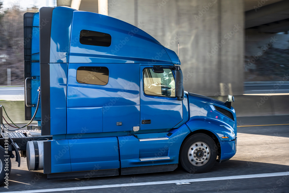 Stylish shine blue big rig semi truck transporting cargo running on the ...
