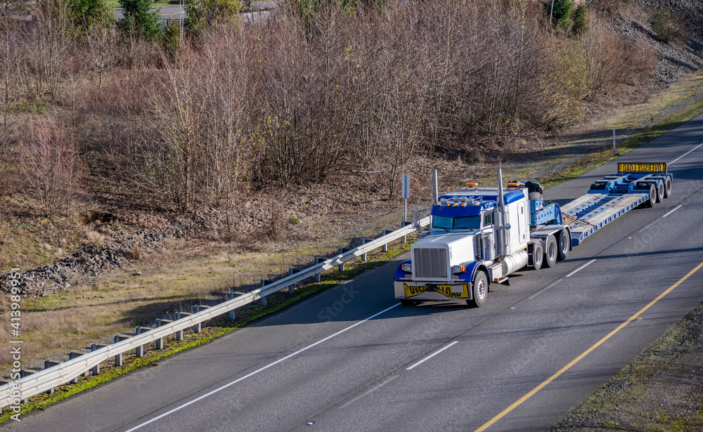 White and blue classic big rig semi truck with empty step down semi ...