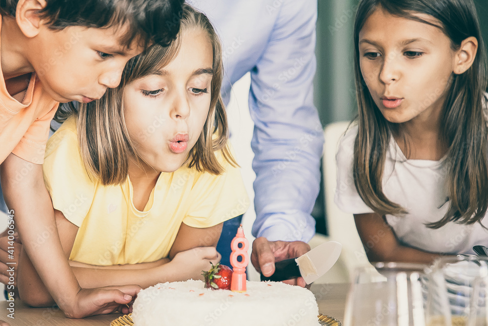 Lovely kids blowing out candle and making wish. Blonde Caucasian girl ...