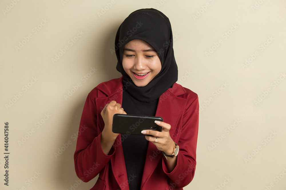 Happy Asian muslim woman excited to play games on her smart phone Stock ...