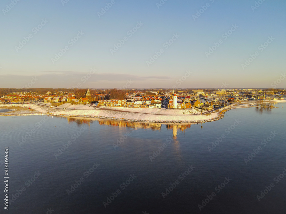 snow covered beach during wnter by Urk lighthouse in the Netherlands ...