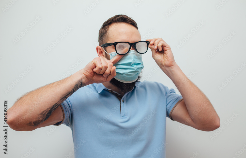 Handsome man with beard wiping blurred foggy misted glasses caused by ...