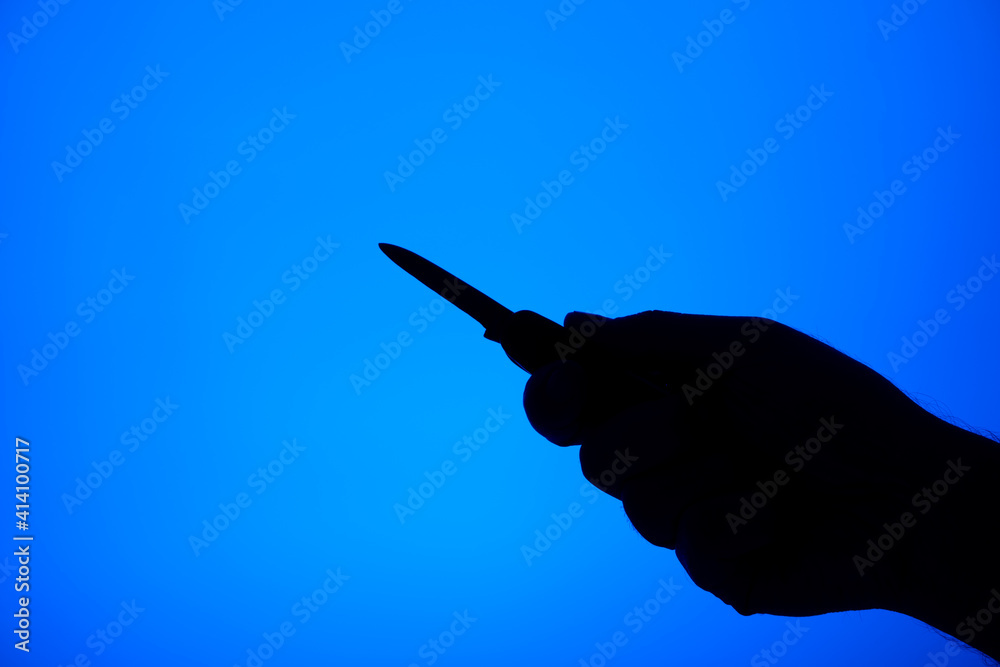 Knife stabbing gesture silhouette black on blue background studio shot ...