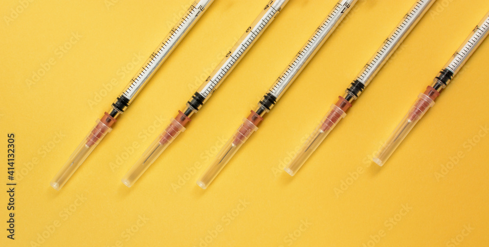 Group of syringes on yellow background. Coronavirus vaccine and ...