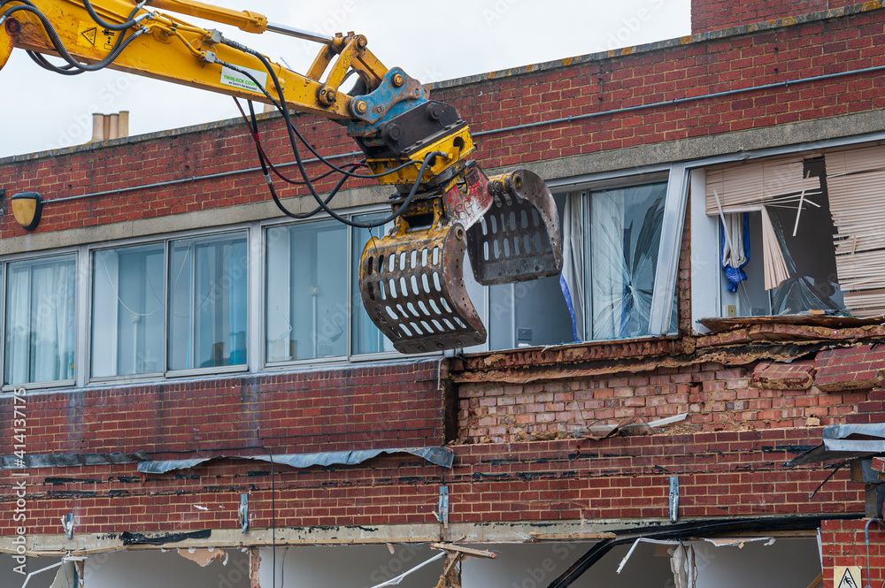 Demolition of an old building with a long reach machine hydraulic jaw ...