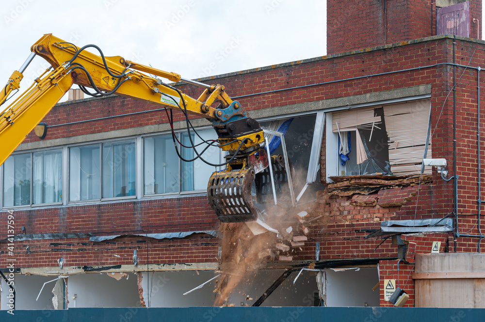 Demolition of an old building with a long reach machine hydraulic jaw ...