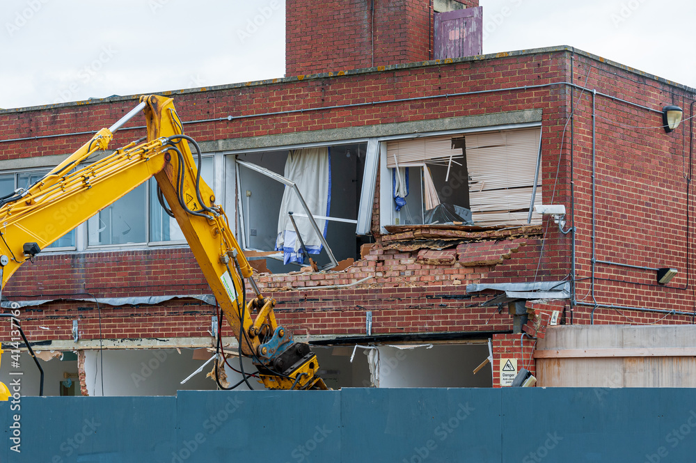 Demolition of an old building with a long reach machine hydraulic jaw ...