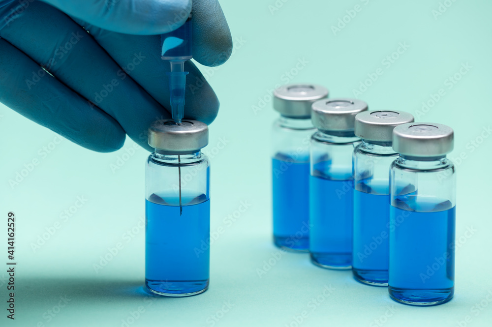 Covid19 Vaccine bottle with a blue liquid and taking the vaccine from ...