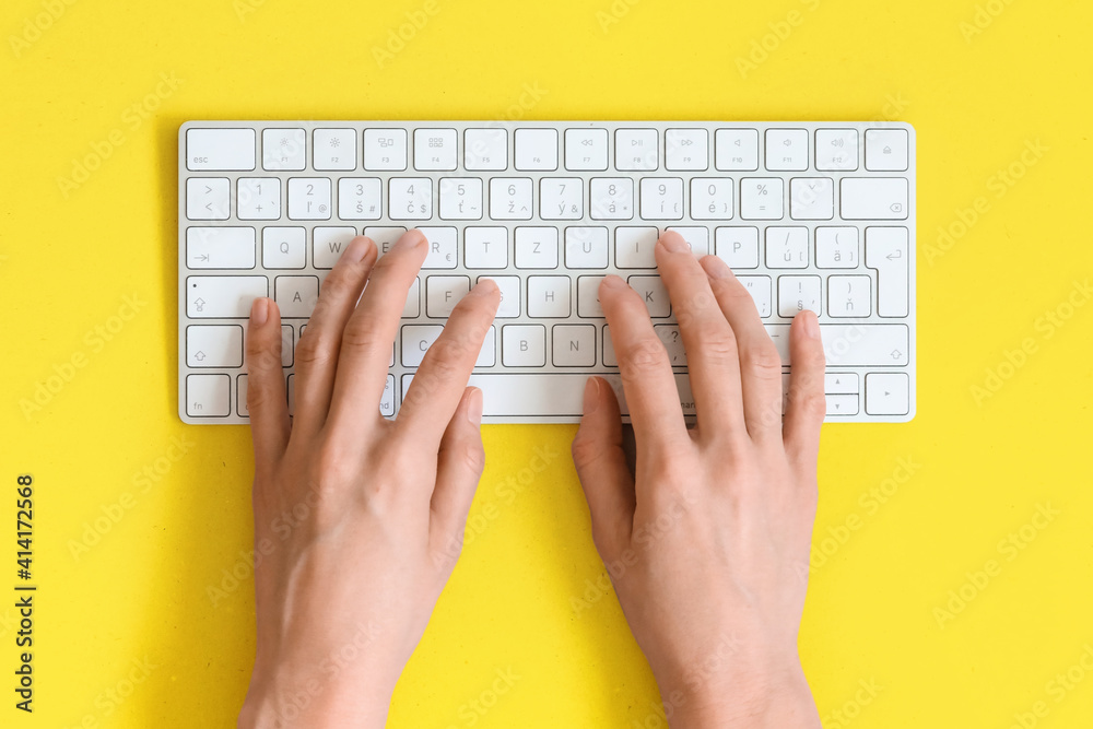 Top view on female elegant hands on a computer keyboard isolated yellow ...