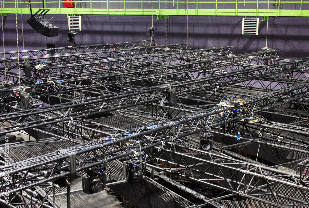 Black steel trusses with moving head spotlight devices are lifted by ...
