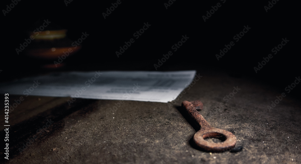 Old and rusty key, on a dusty table, with little light in a mysterious ...